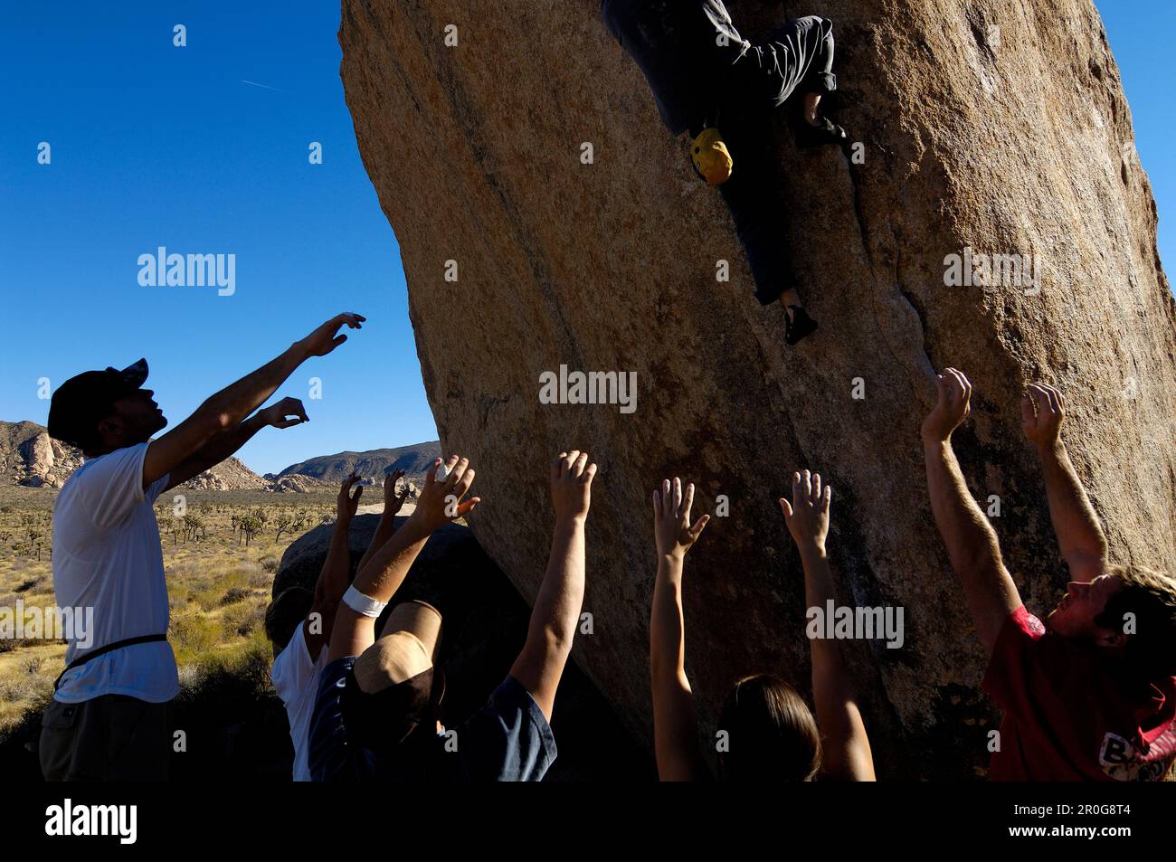People with extended arms standing in front of a boulder, Yoshua Tree ...