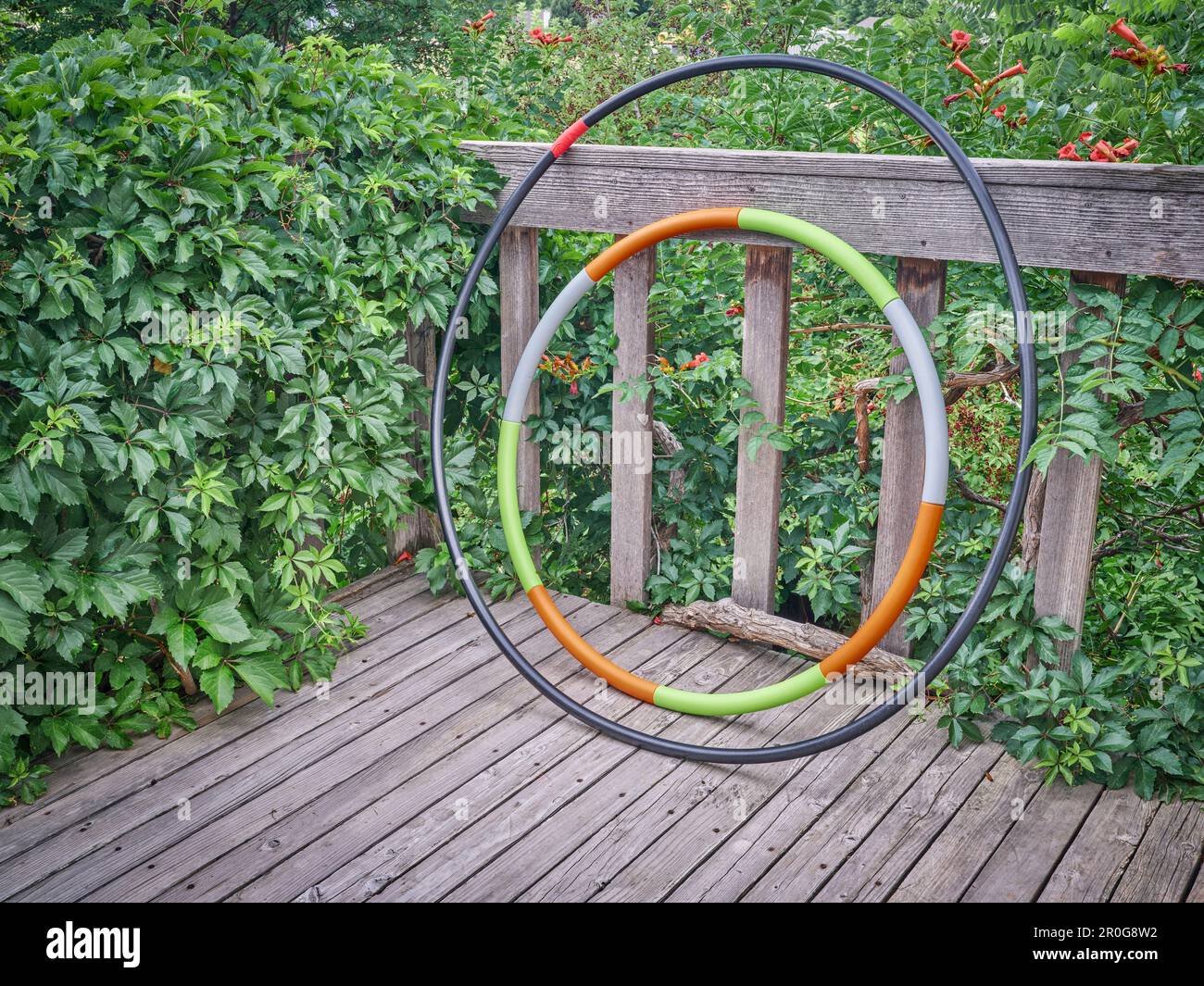 weighted hula hoop and one home made from a sprinkler pipe on a wooden backyard deck in summer ...