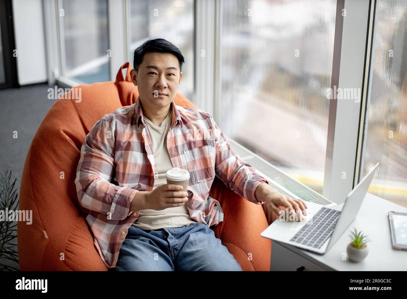 Portrait of casually dressed positive indian man, sitting on orange ...