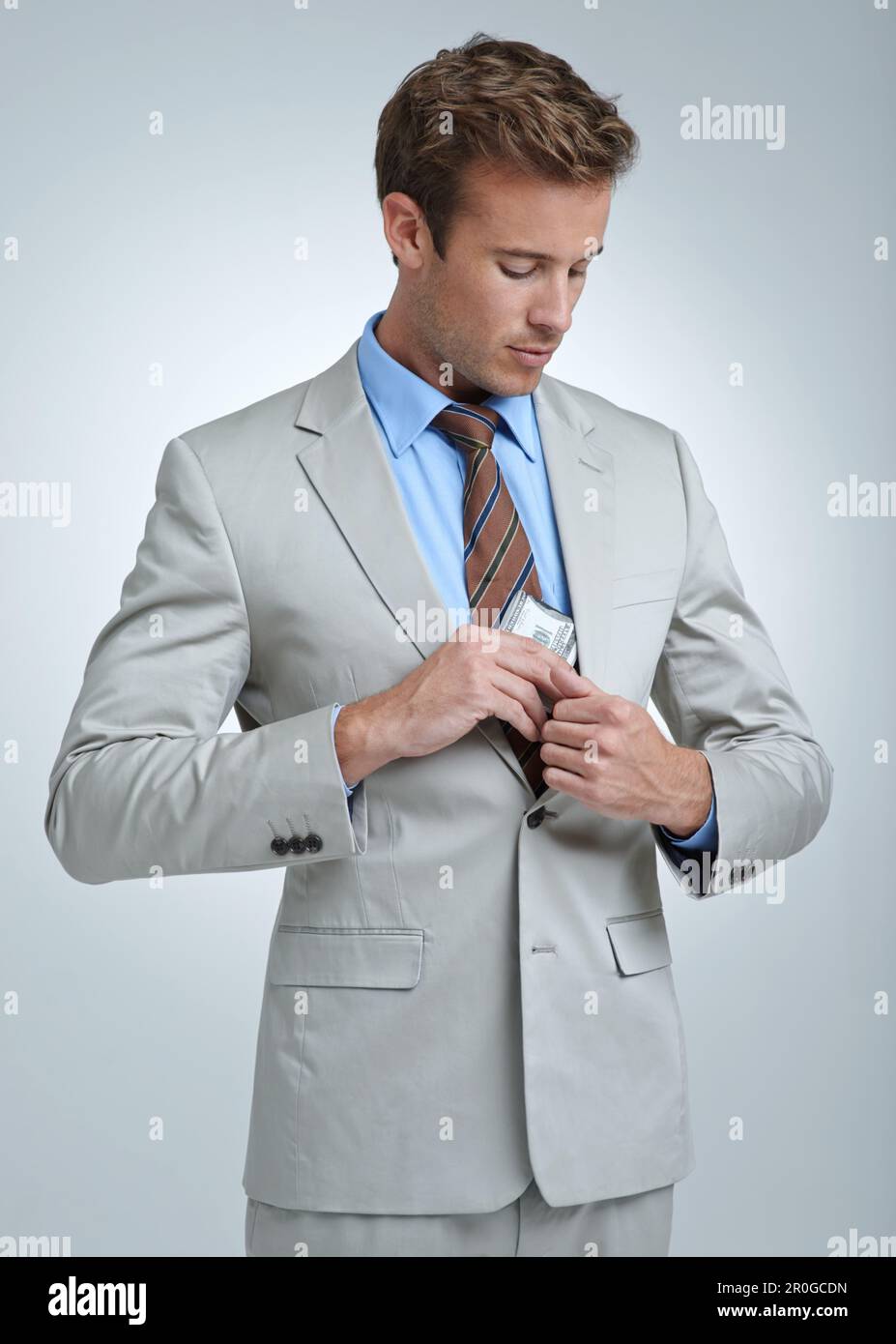 Keeping some profits for himself. A young businessman putting a wad of ...