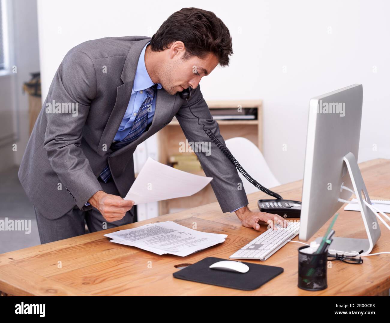 Getting swamped at work. A handsome businessman multitasking at his ...
