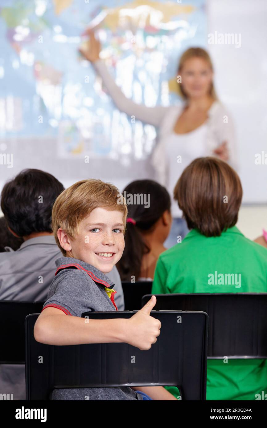 Kid, portrait and thumbs up of student in classroom, elementary school ...