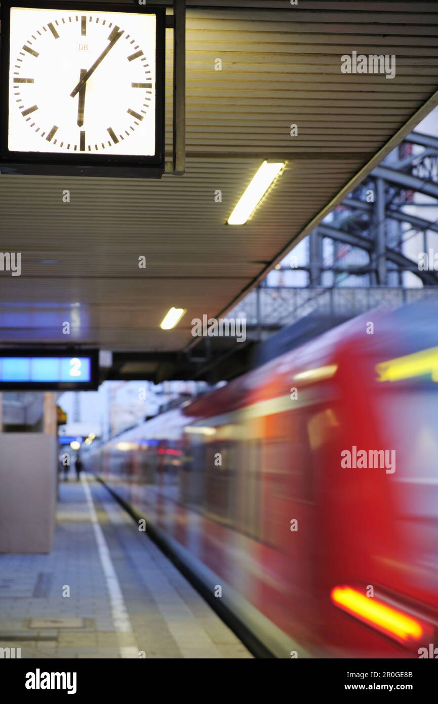 Platform with clock, suburban train in motion out of focus in the ...