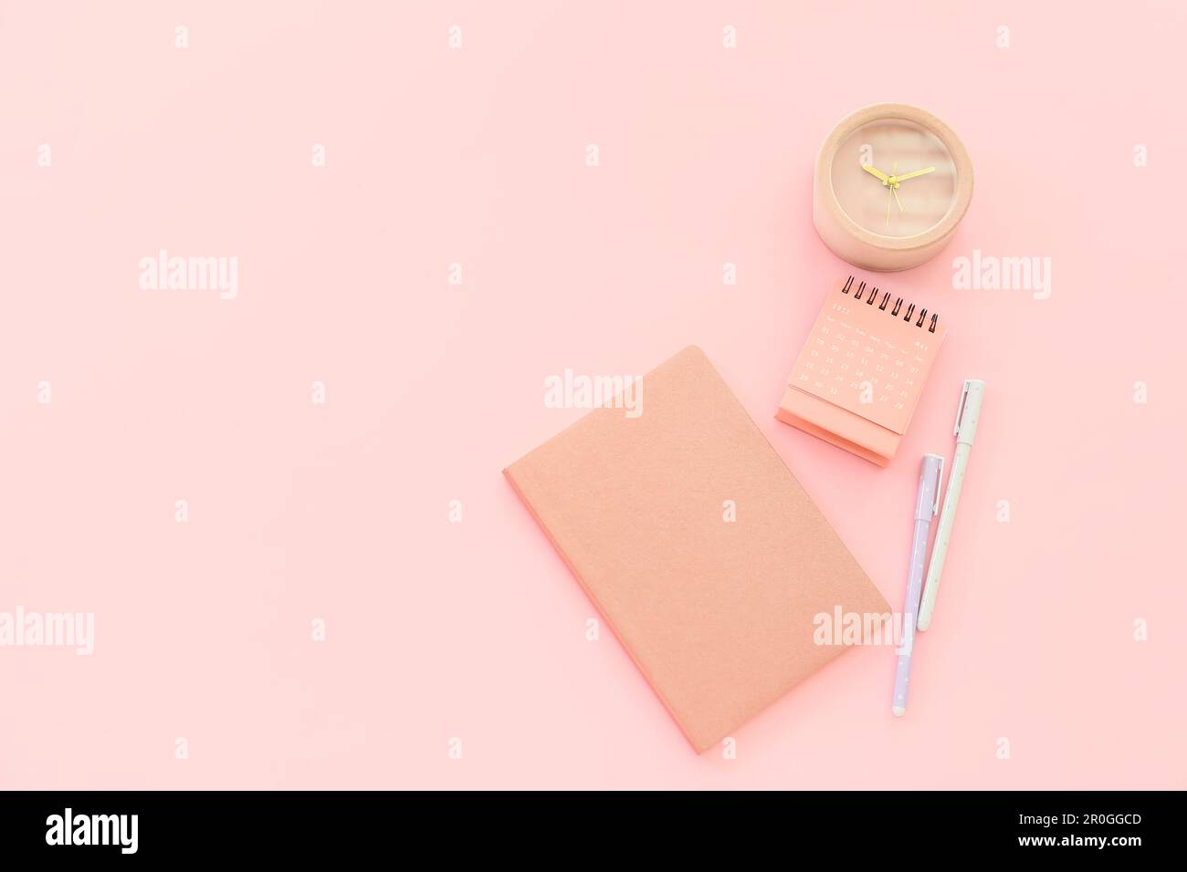 Flip paper calendar with alarm clock and notebook on pink background ...