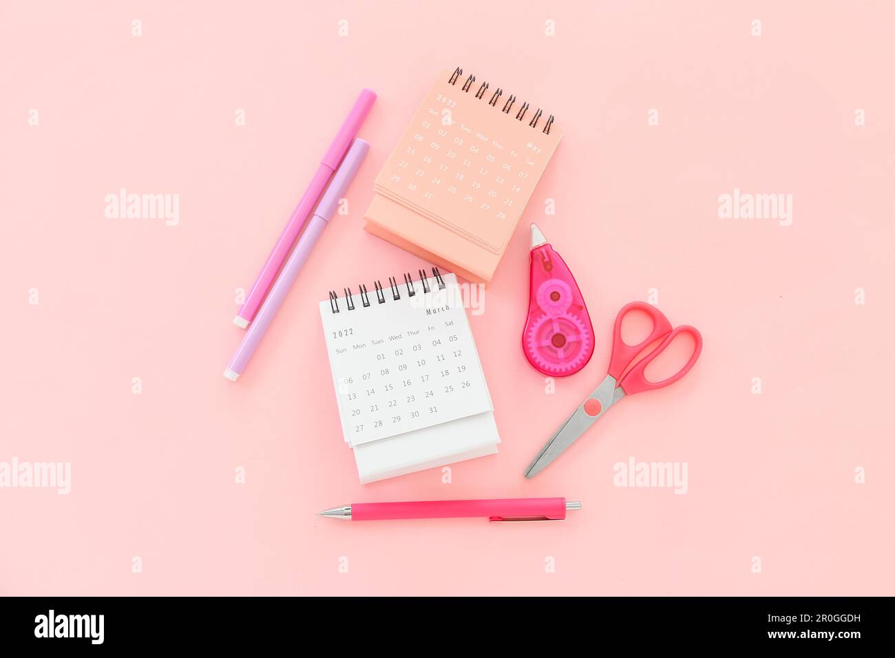 Flip paper calendars and stationery on pink background Stock Photo - Alamy