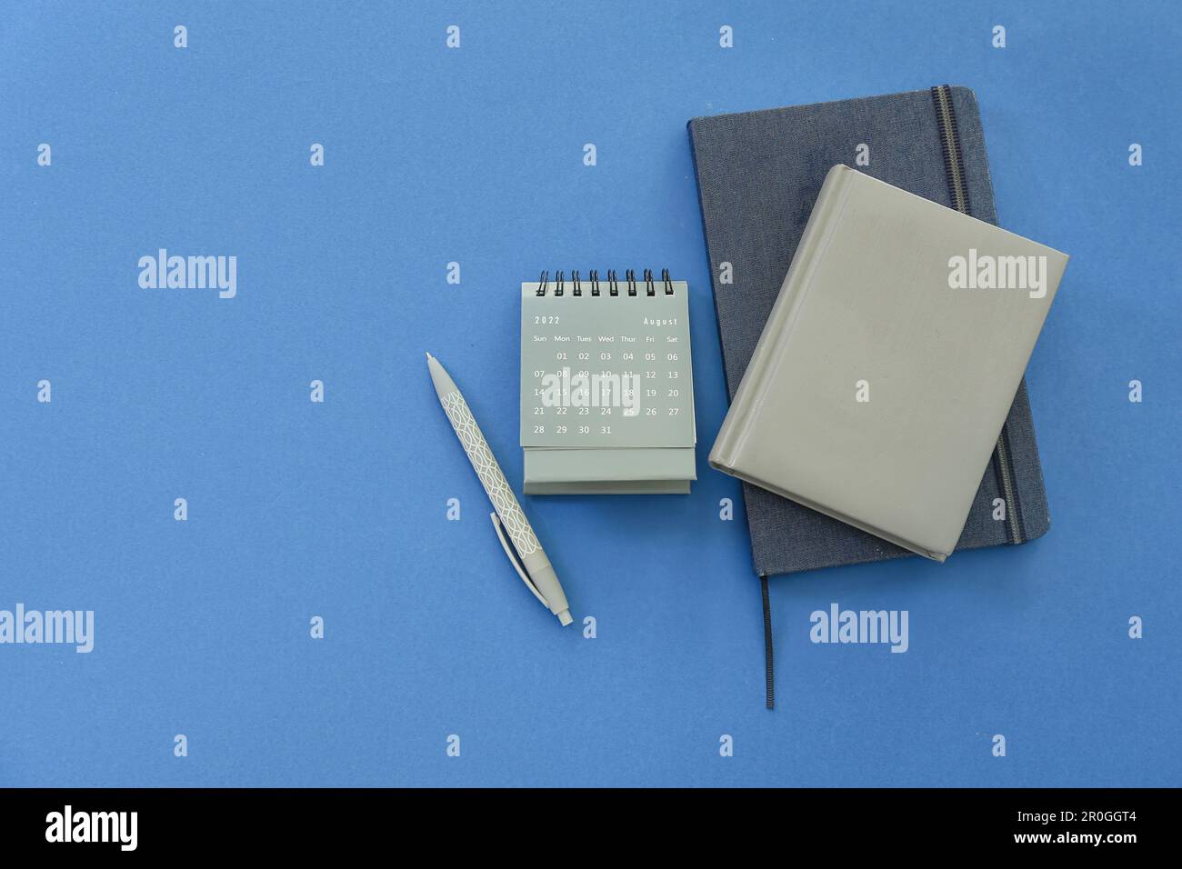 Flip paper calendar for August with notebooks and pen on blue ...