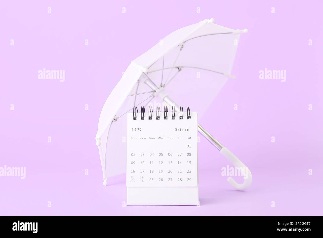 Flip paper calendar for October and umbrella on purple background Stock ...