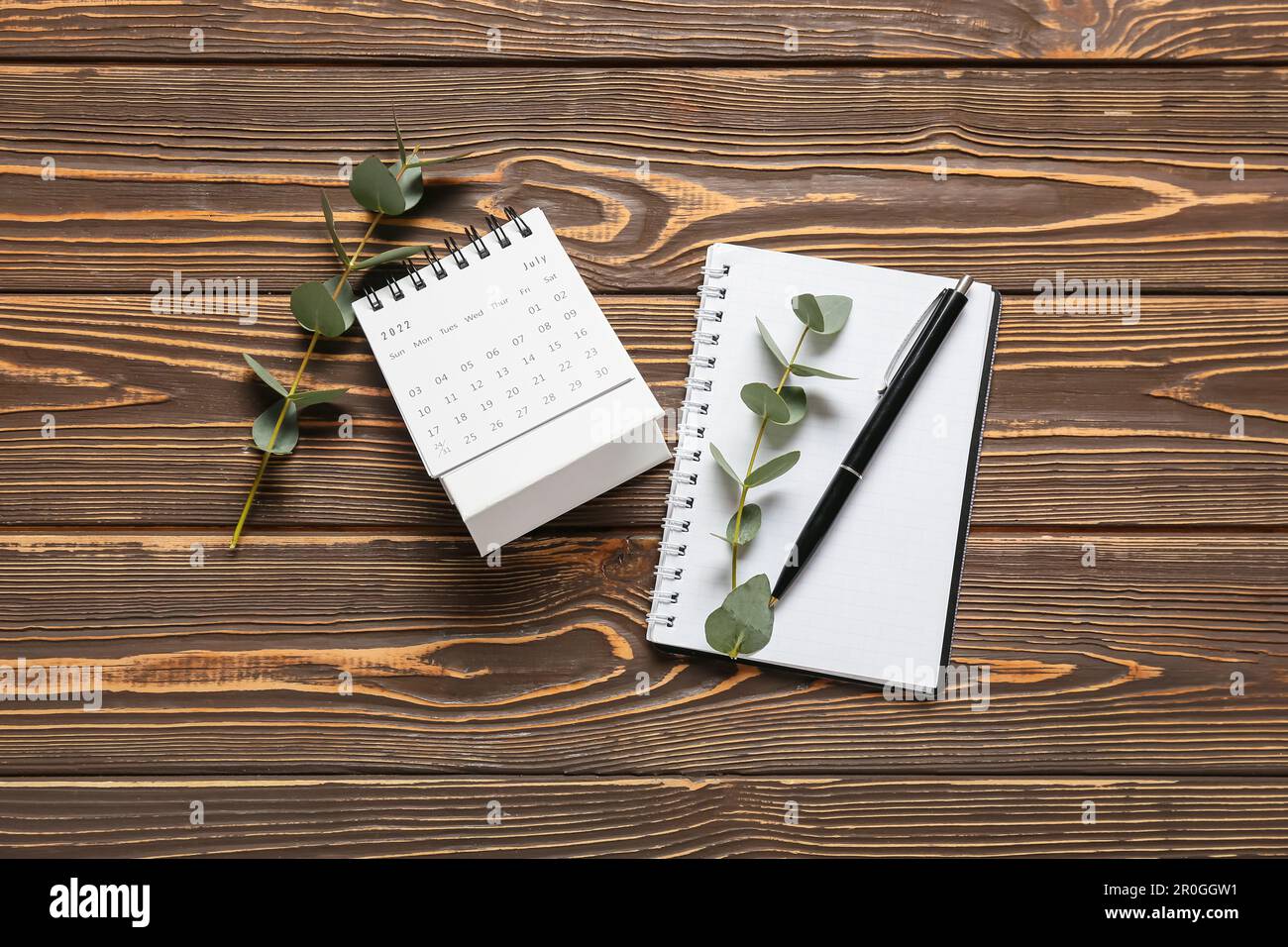 Flip paper calendar with eucalyptus branches and notebook on wooden ...