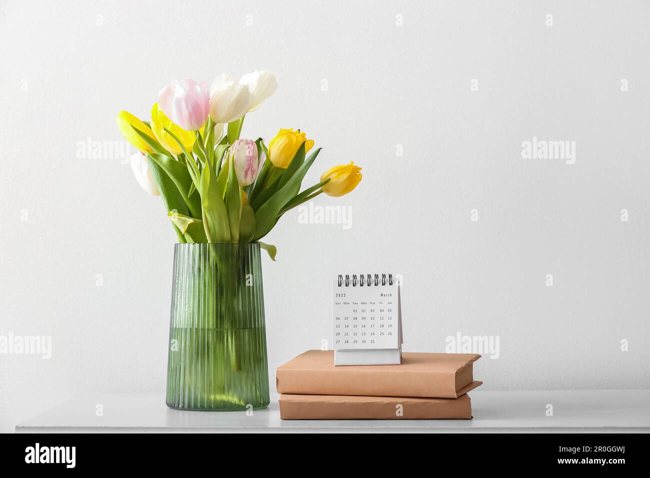Flip paper calendar, notebooks and vase with flowers on table Stock ...