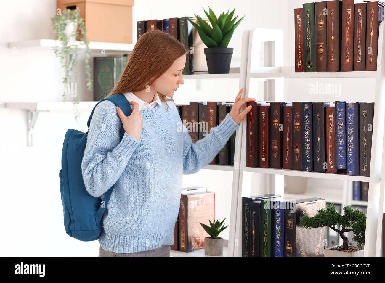 Female student taking book from shelf in library Stock Photo - Alamy