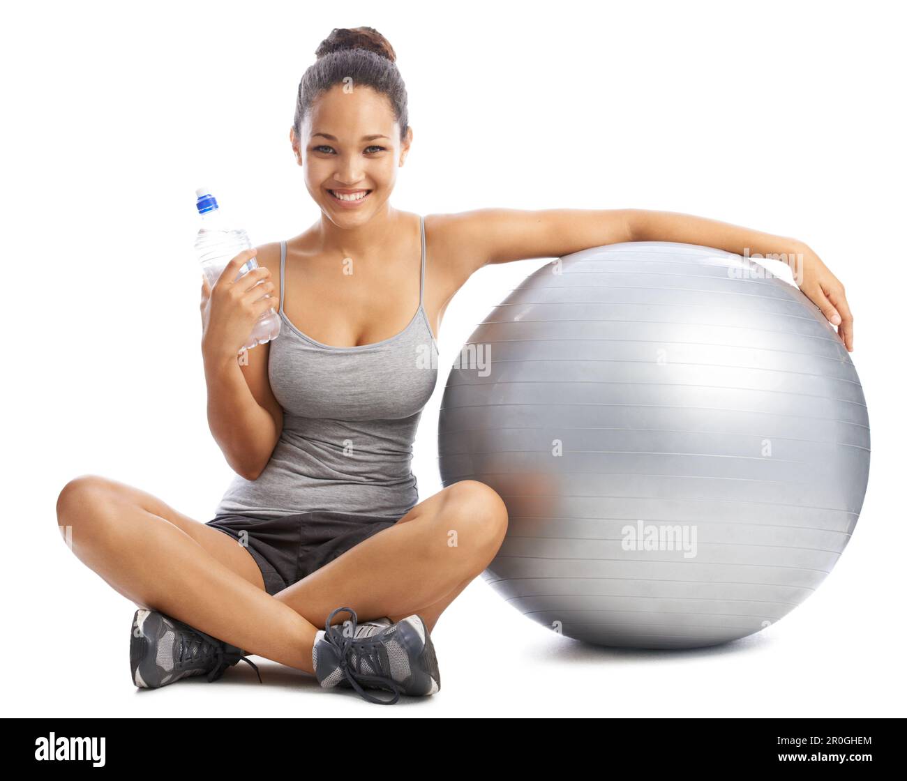 Keeping hydrated while working up a sweat. A young woman sitting next to an exercise ball ...