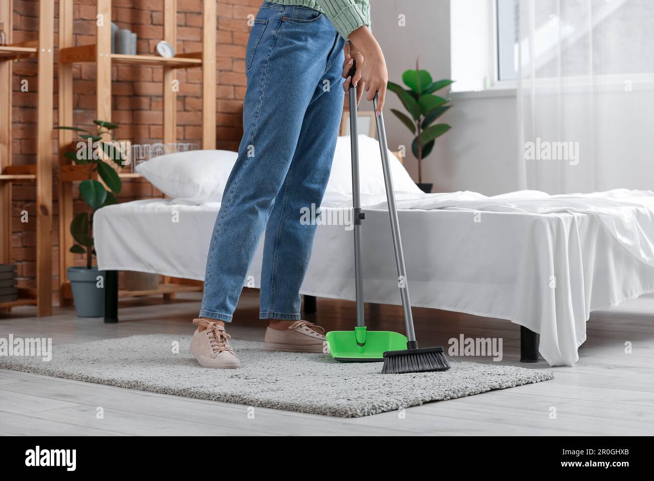 Young woman sweeping floor in bedroom Stock Photo - Alamy