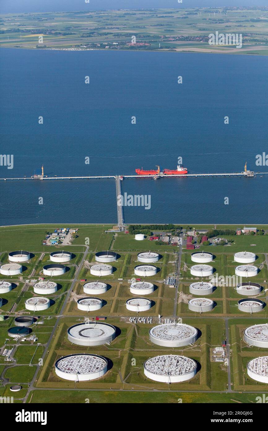 Aerial shot of oil tanker at oil pier, oil tanks in foreground ...