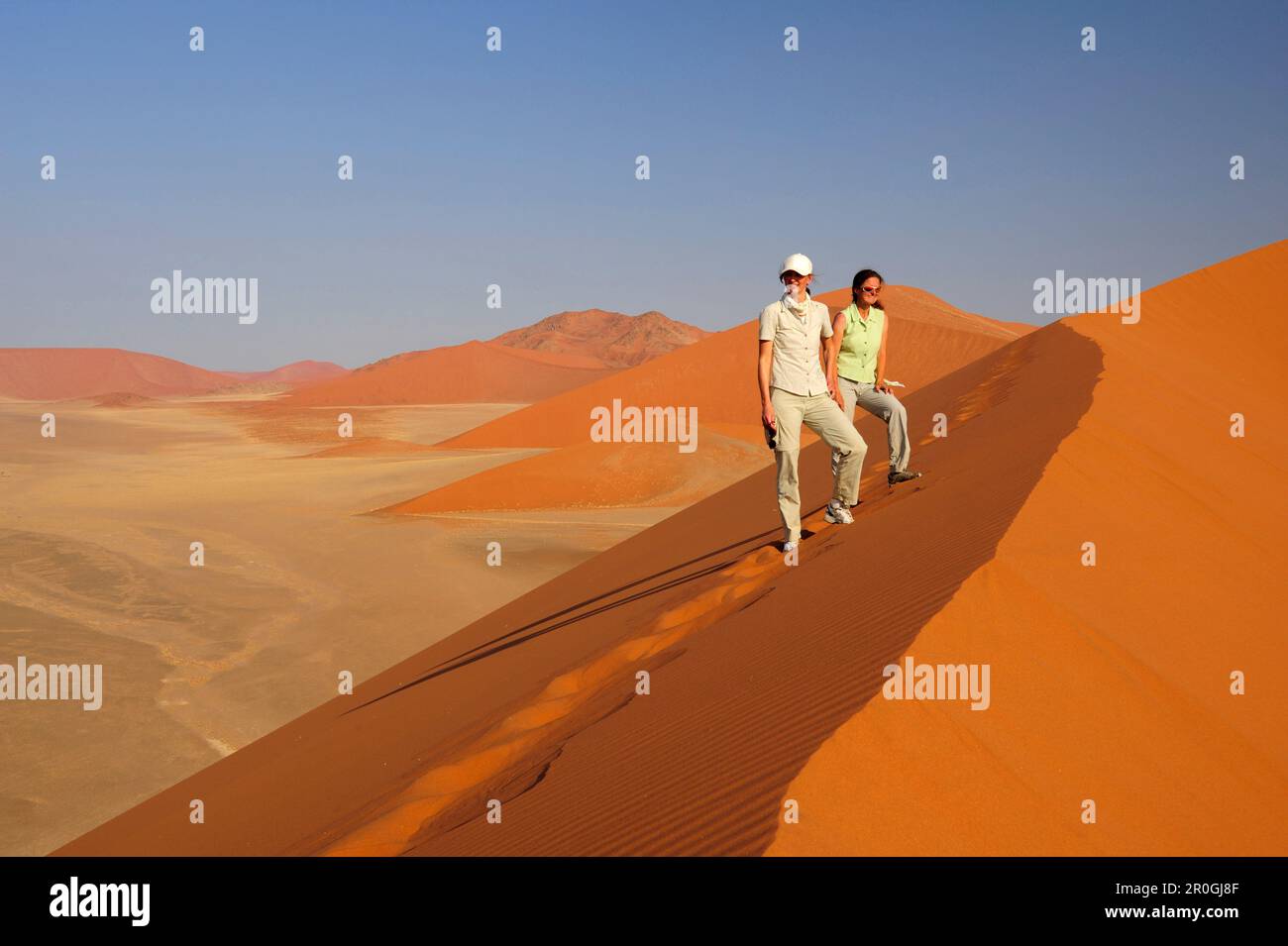 Two women standing on red sand dune in Sossusvlei, dune 45, Sossusvlei, Namib Naukluft National ...