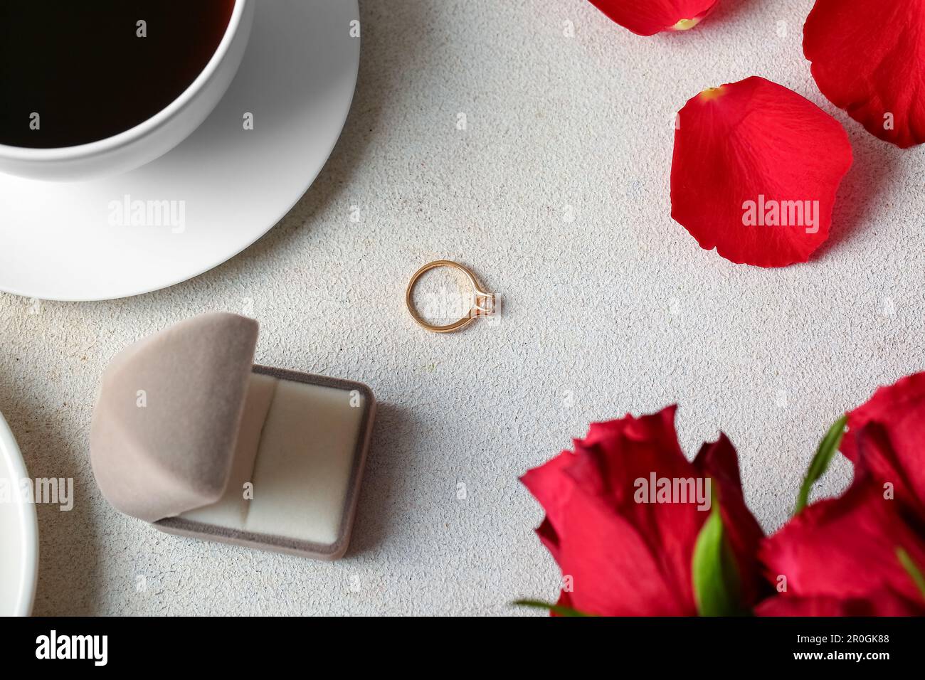 Box with engagement ring, coffee cup and roses on white background ...