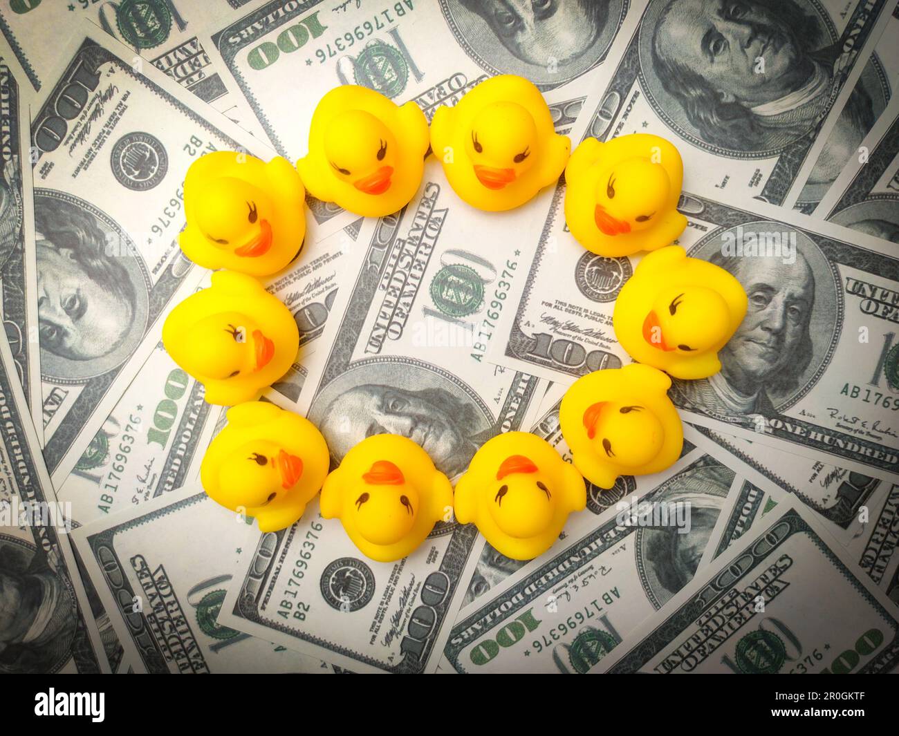 The yellow rubber ducks on a pile of money of hundred dollar bills ...