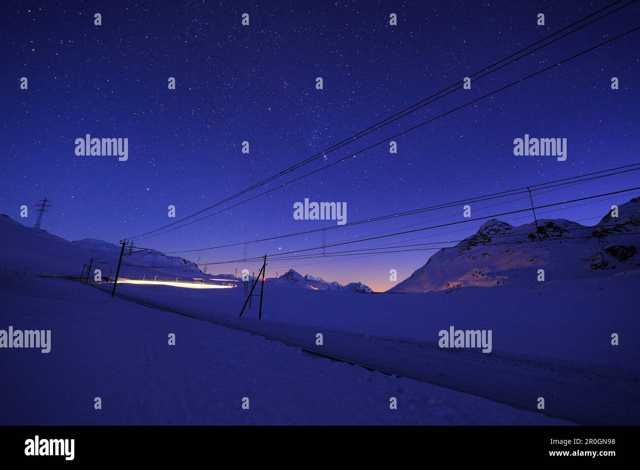 Train of Rhaetien railway as light beam driving by night through winter ...