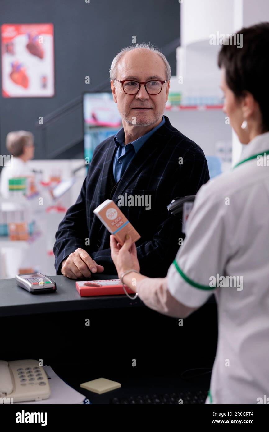 Old man in glasses waiting for drugstore cashier scanning product to ...