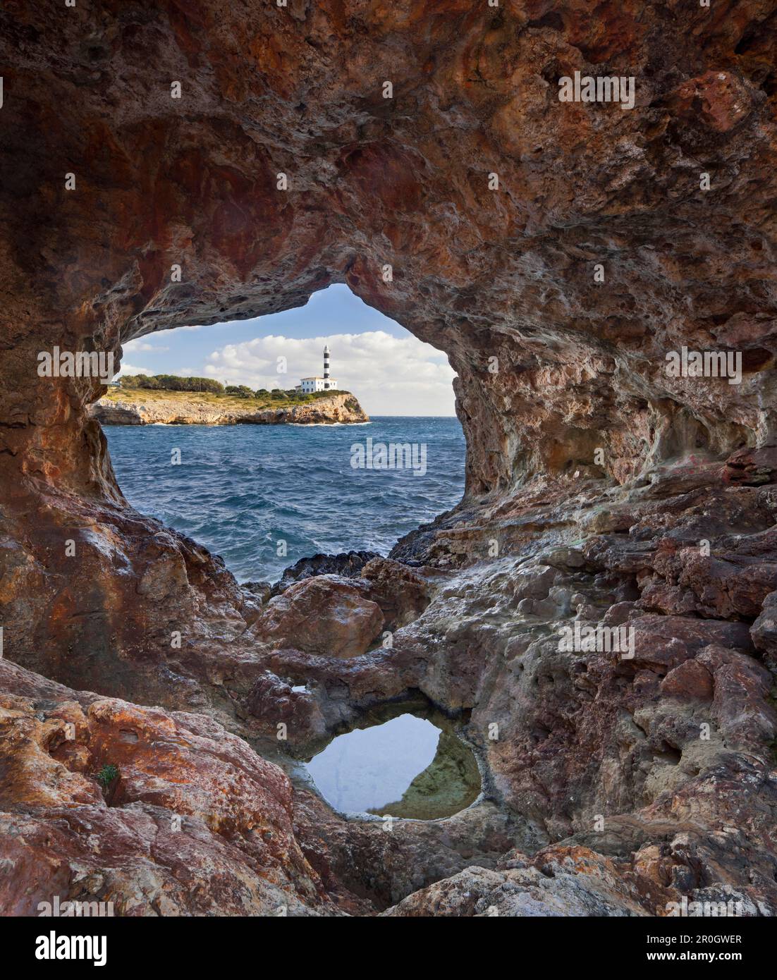View through hole in a rock onto lighthouse of Portocolom, Punta de s ...