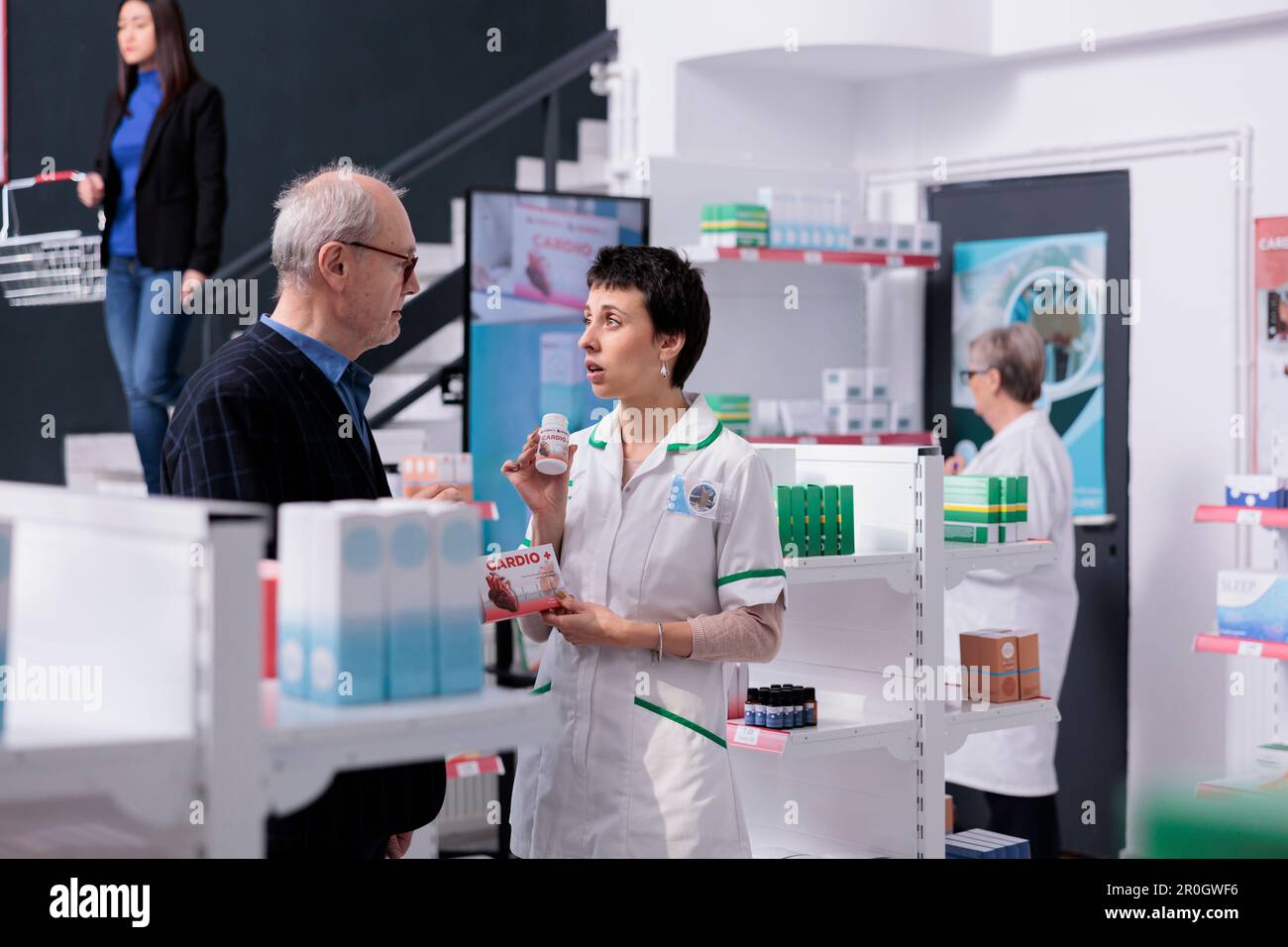Medical employee showing senior customer heart pills and giving ...
