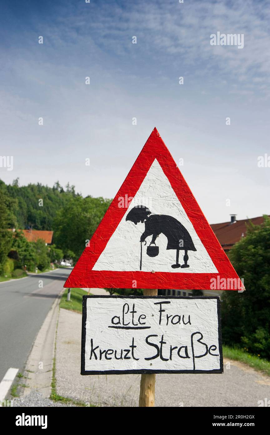 Homemade street sign showing an old woman crossing the road, near ...