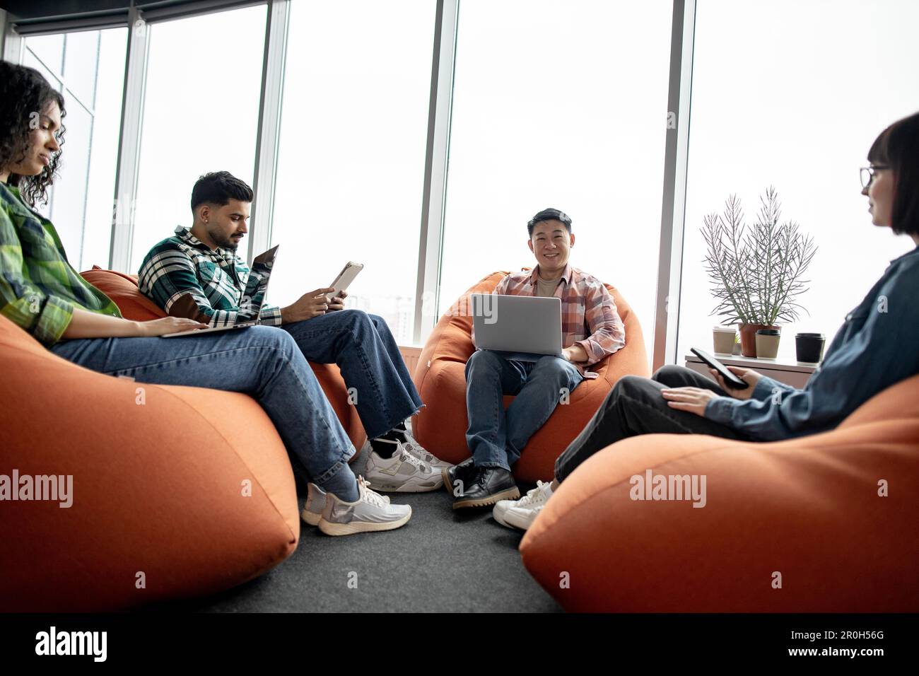 Confident asian man in casual wear talking to multiethnic colleagues ...