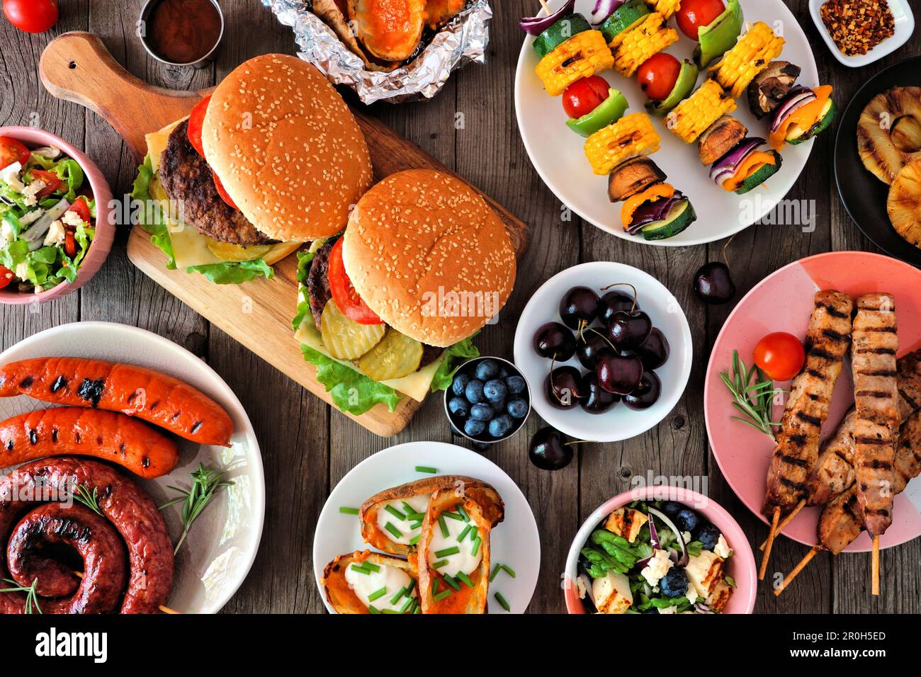 Summer BBQ or picnic food table scene. Selection of burgers, grilled ...