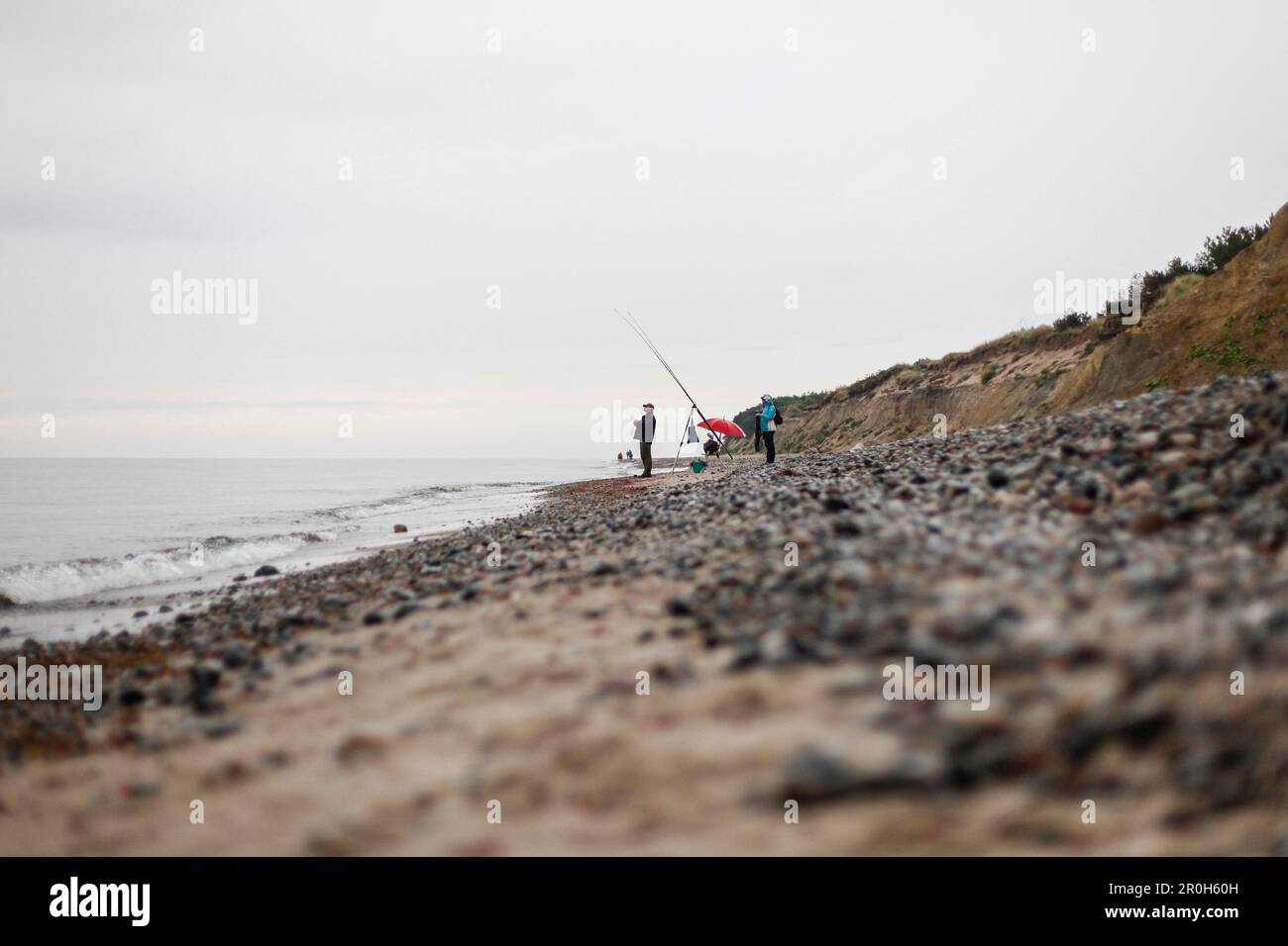Pebbbles beach with fisherman in the rain, Baltic Sea, beach near ...