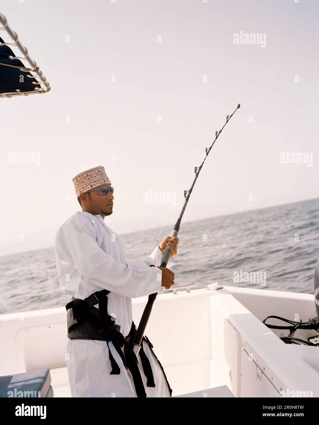 OMAN, Muscat, young man in traditional clothing fishing on boat Stock ...