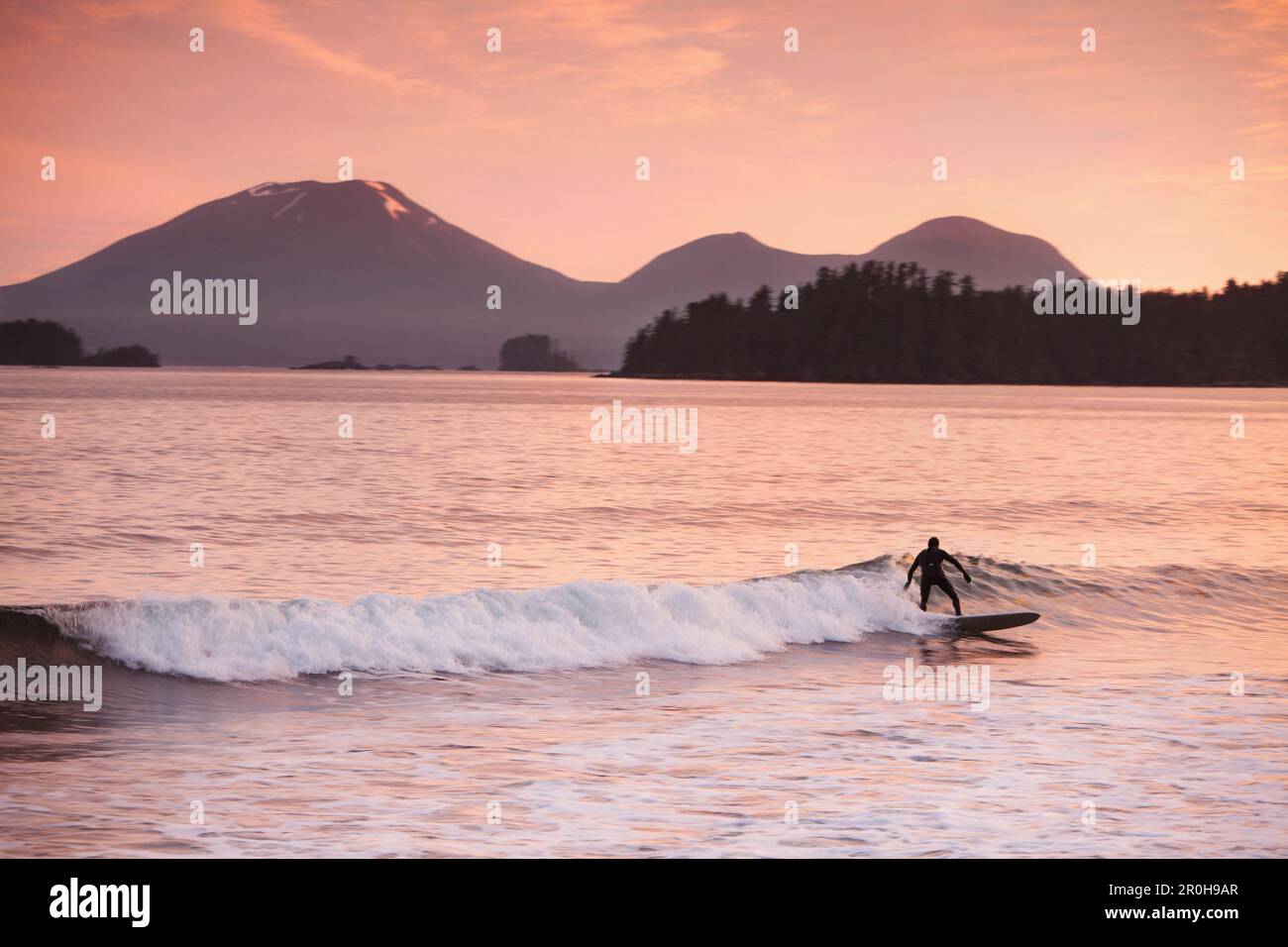 ALASKA, Sitka, a surfer catches waves created by the tidal shift ...