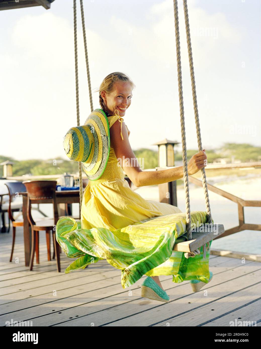 Aruba, Surfside Marina, a young woman sits on a swing smiling at ...