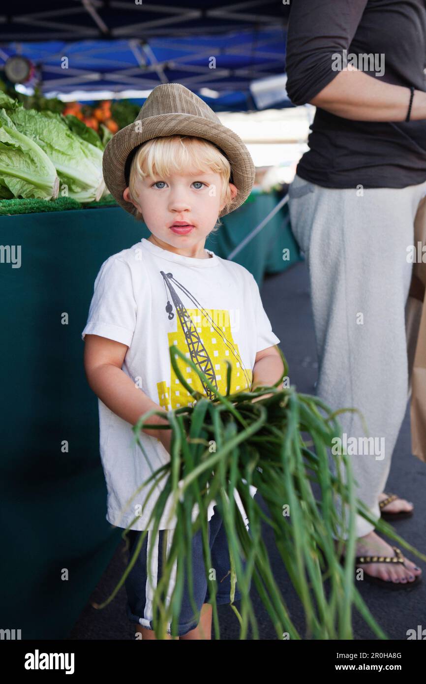 USA, California, Malibu, a young boy holds produce for his mom at the ...