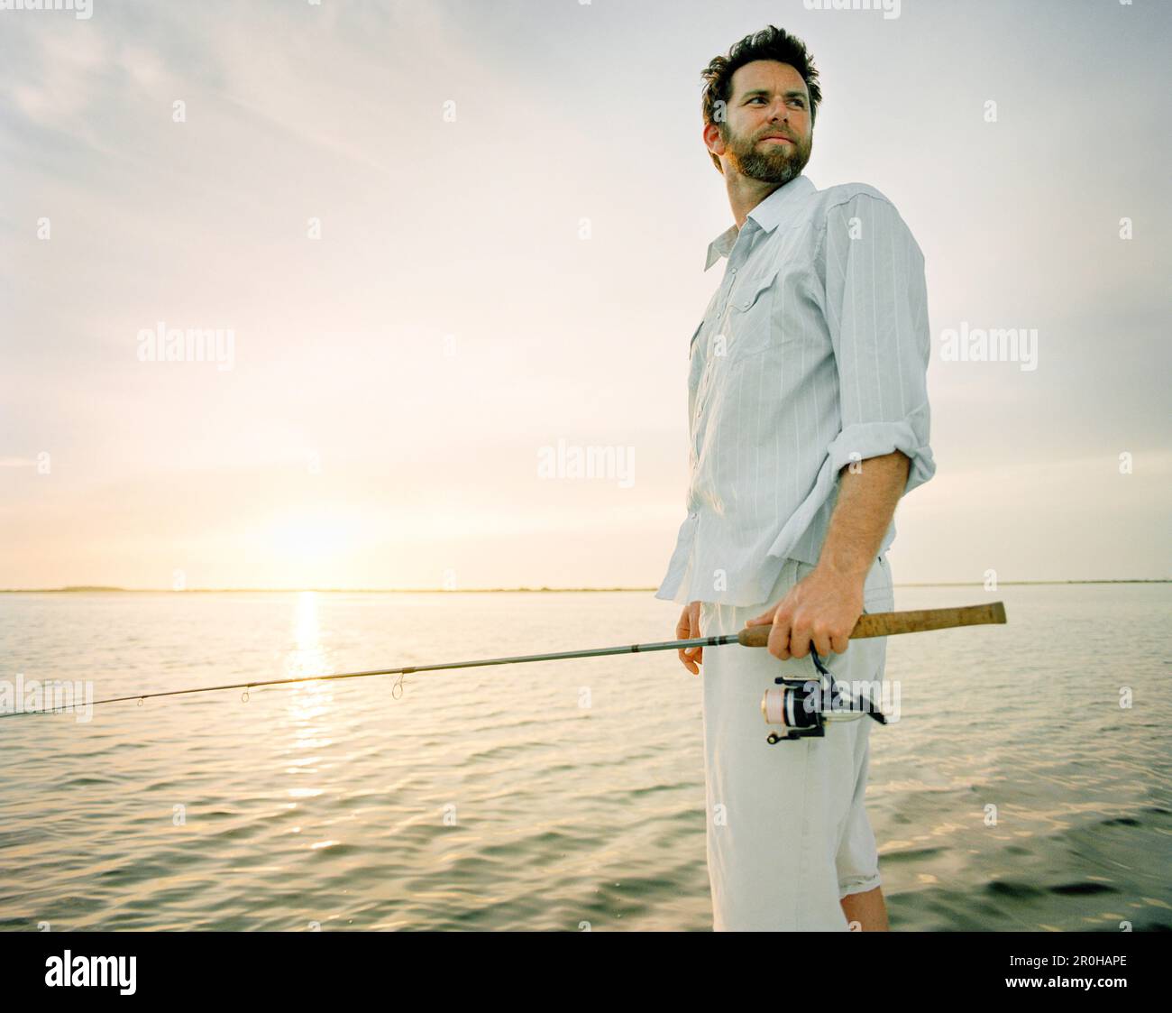 USA, Florida, fisherman holding fishing rod boat at dawn, New Smyrna ...
