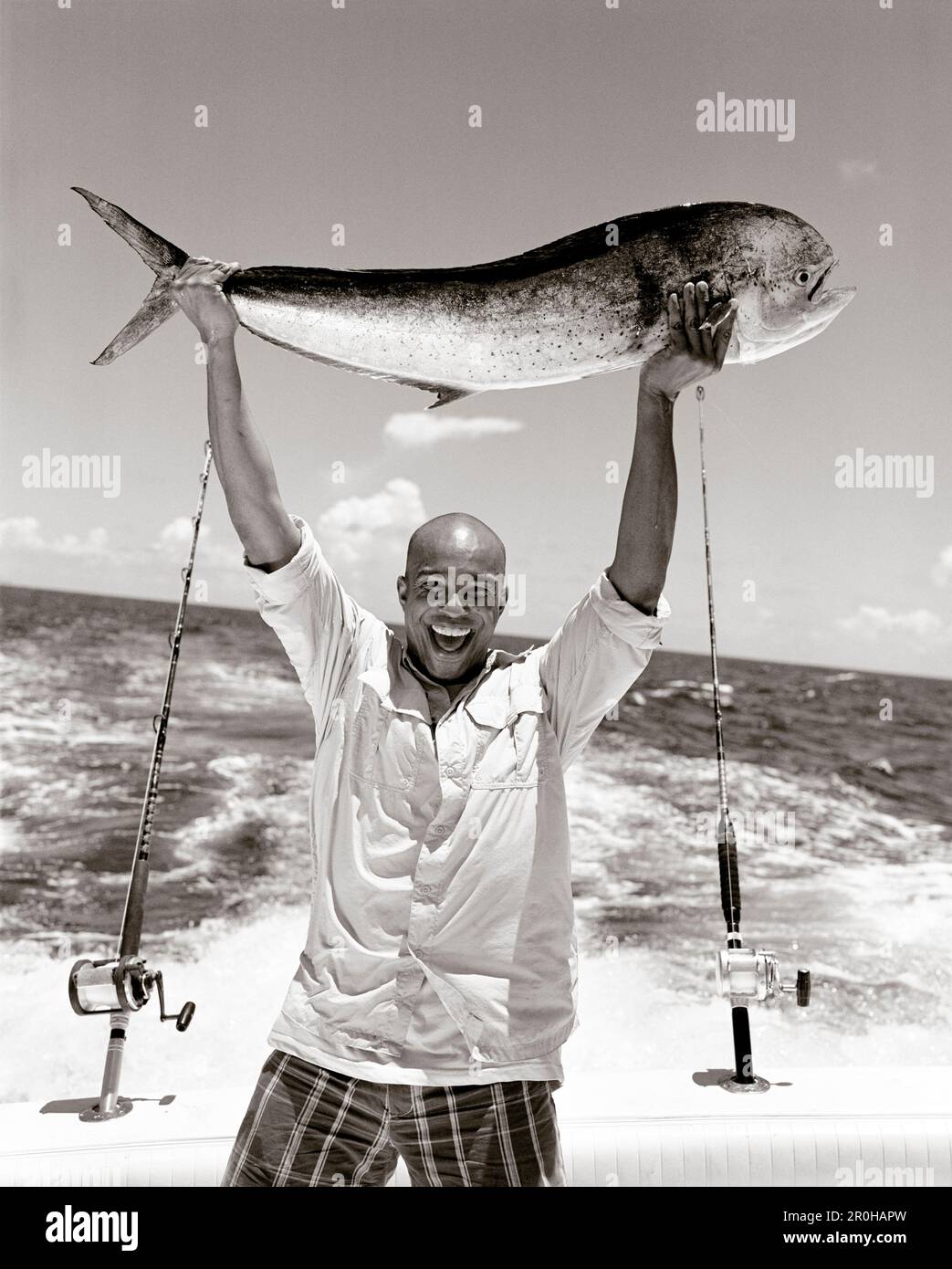 USA, Florida, man on boat holding up the catch of the day, Mahi Mahi ...