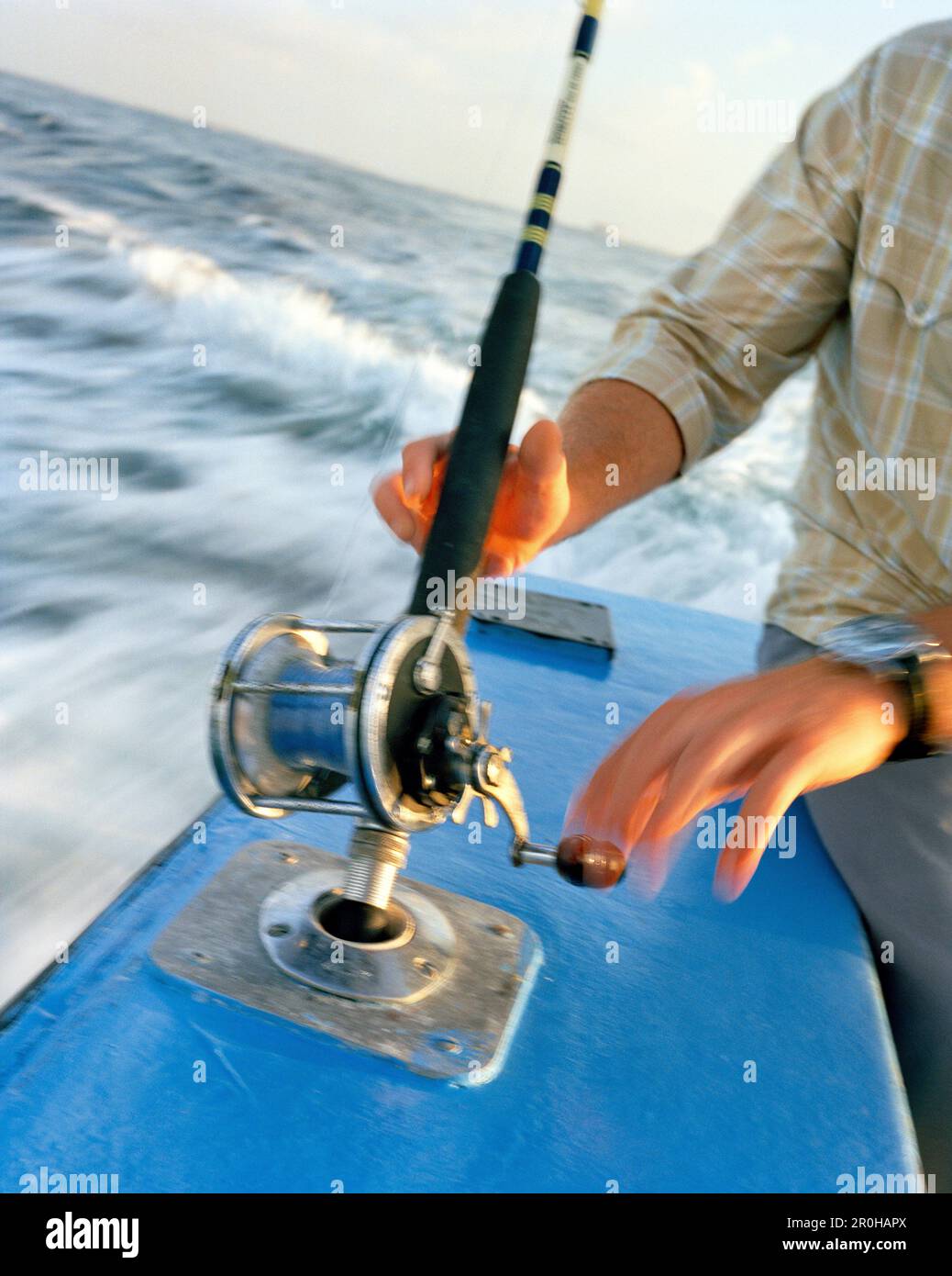 USA, Florida, man sitting on fishing boat preparing to reel in a fish ...