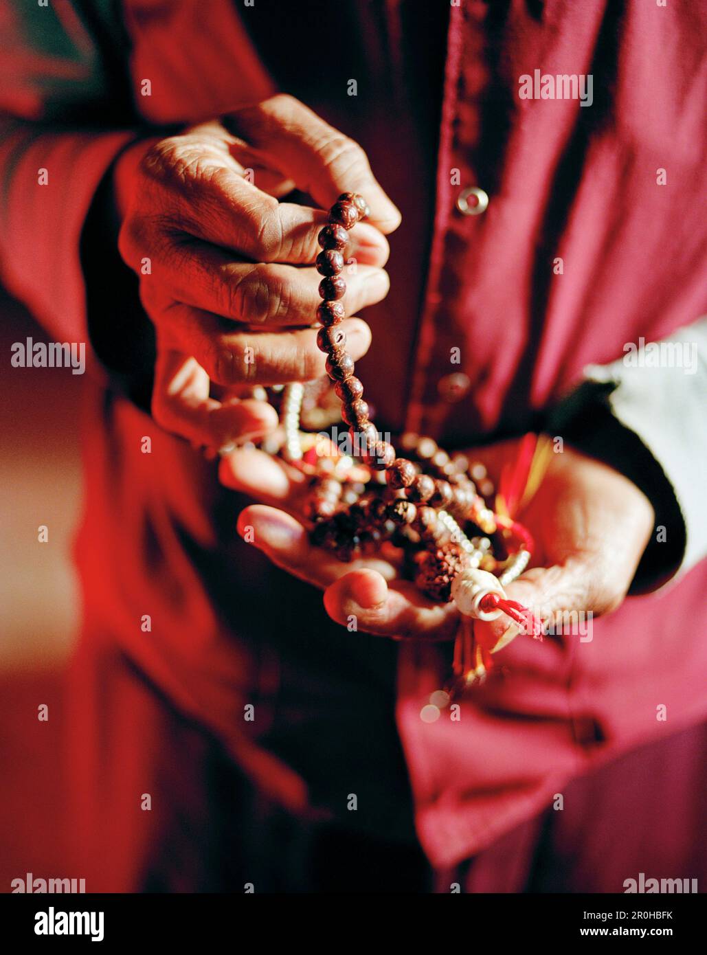 INDIA, West Bengal, midsection of lama holding string of beads ...