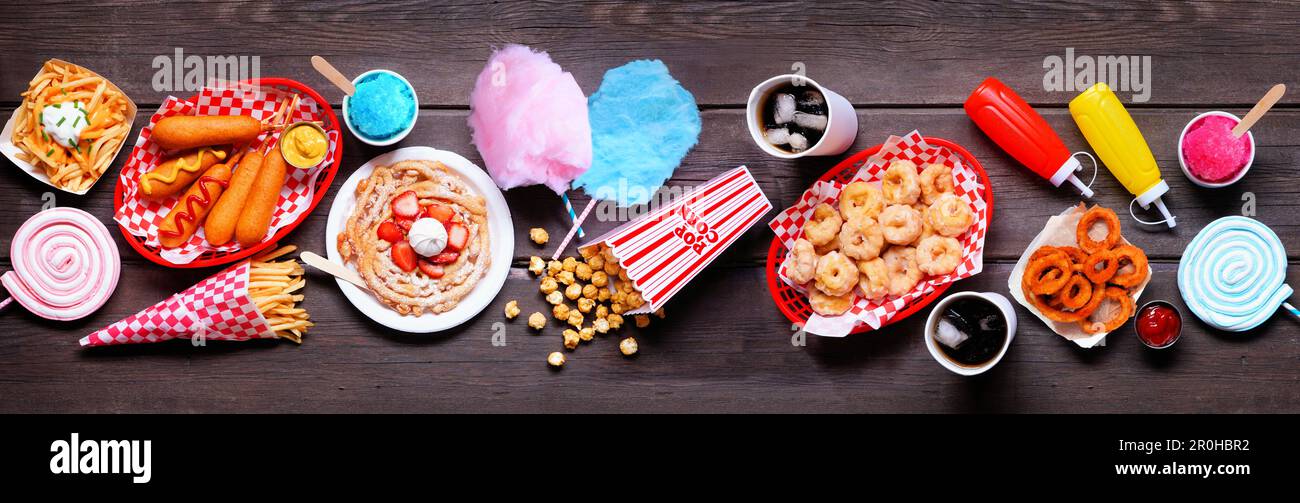 Carnival theme food table scene over a dark wood banner background ...