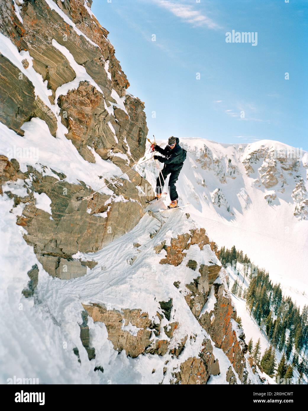 USA, Utah, skier climbing around rocky cliff, holding onto a rope, High ...