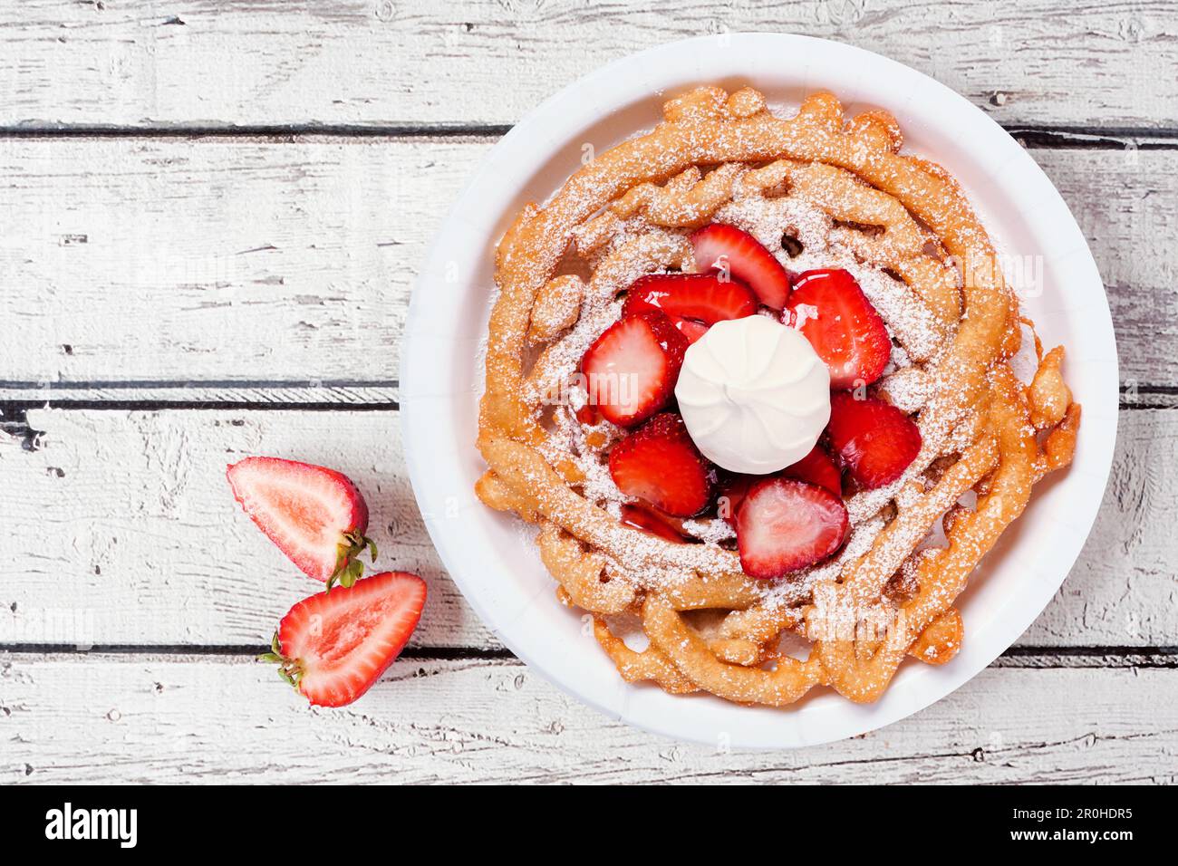 Strawberry funnel cake overhead view on a white wood background ...