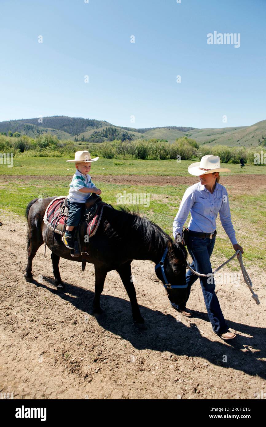 USA, Wyoming, Encampment, a wrangler leads a young boy on a pony, AbarA ...