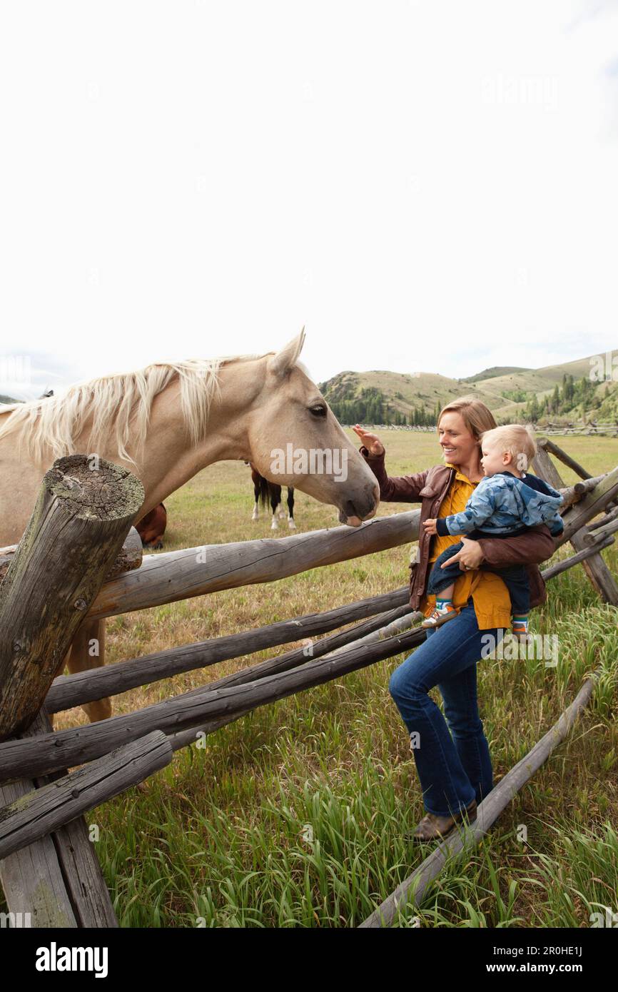 USA, Wyoming, Encampment, a woman and her son pet a horse on the nose ...