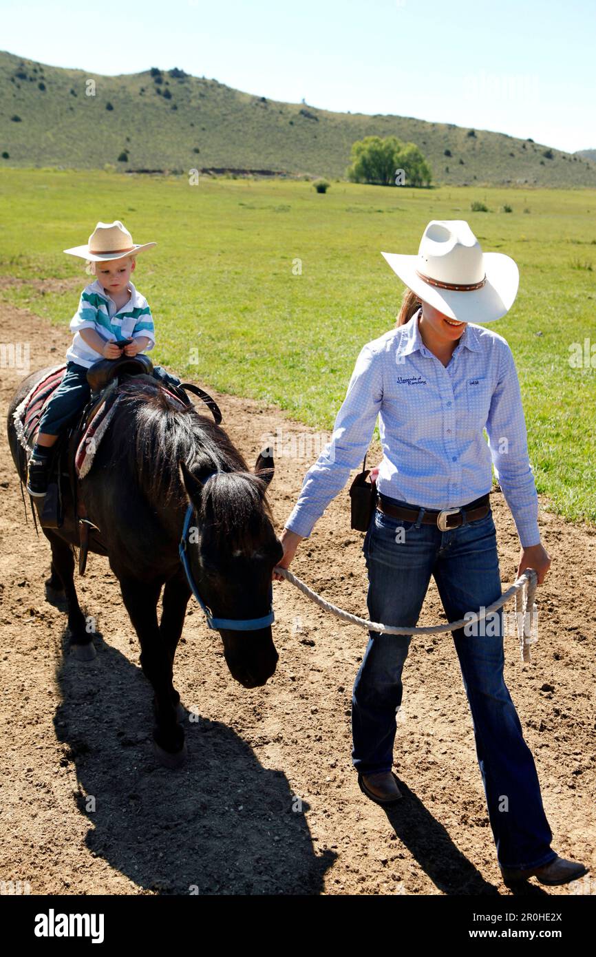 USA, Wyoming, Encampment, a wrangler leads a young boy on a pony, AbarA ...