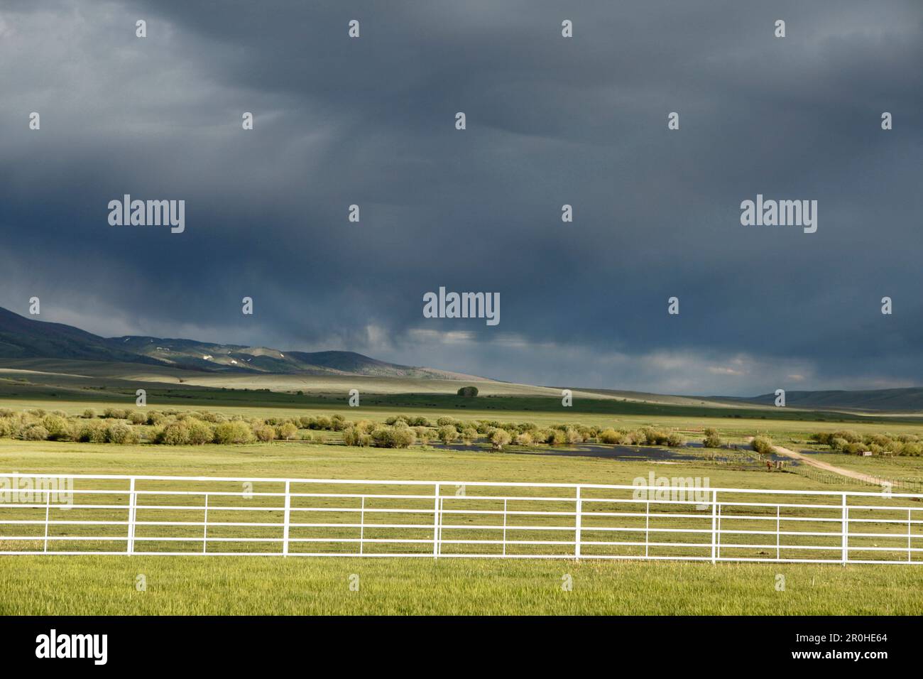 USA, Wyoming, Encampment, a white fenceline and open rolling landscape ...