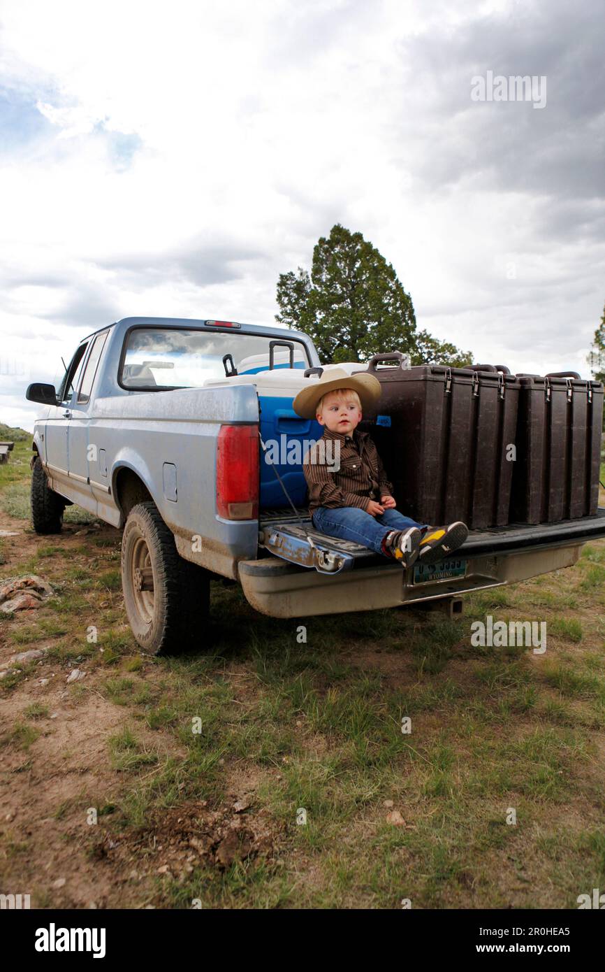 USA, Wyoming, Encampment, a little boy in a cowboy hat sits on the back ...