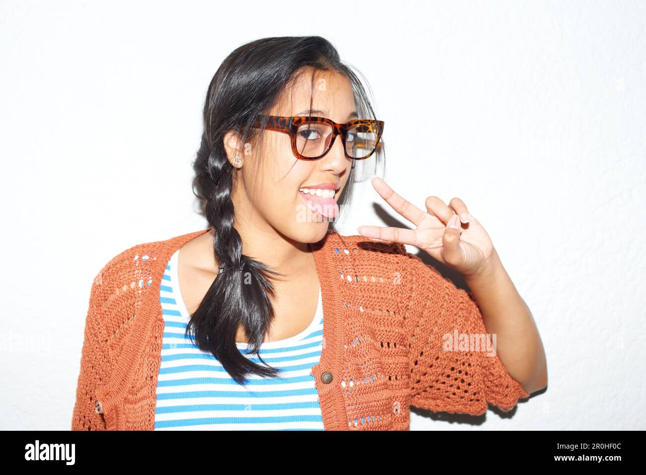 Feeling cheeky - Hipster attitude. Cute young hipster girl giving the V ...