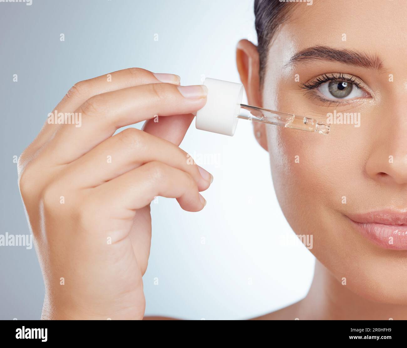 Closeup portrait of beautiful woman using dropper to apply face serum ...