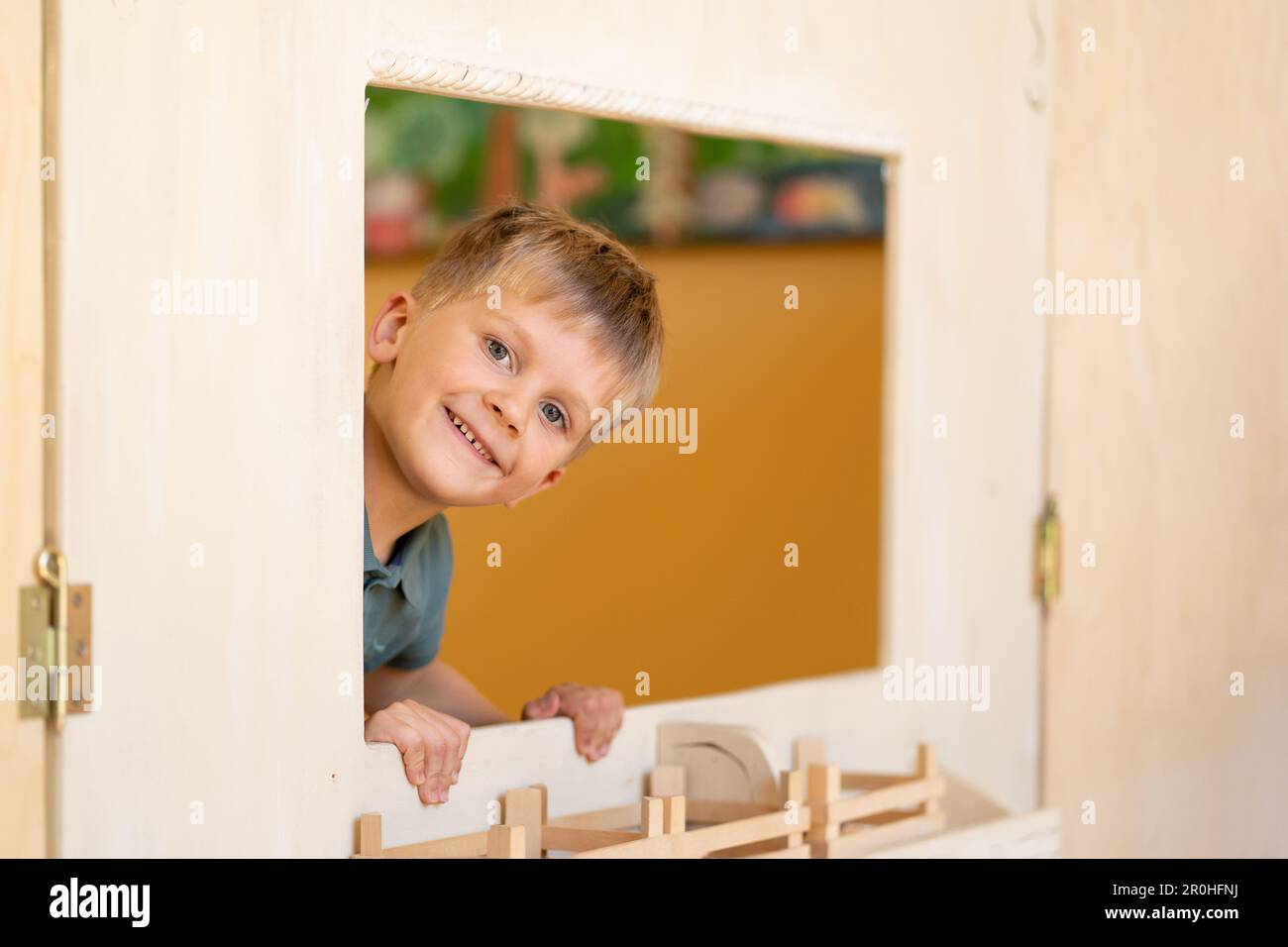 Portrait of happy smiling boy is peeking out of the window of the ...