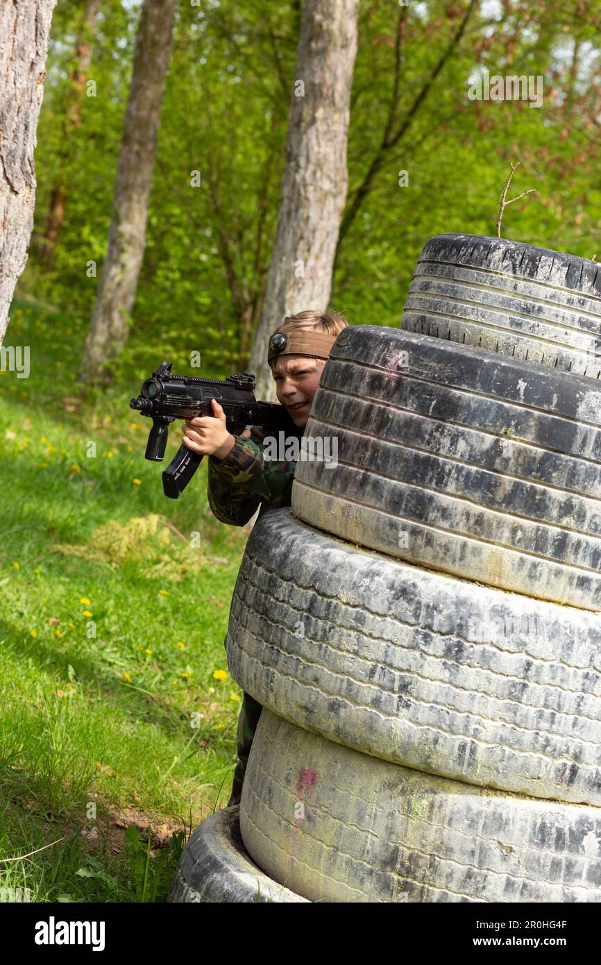 Boy weared in camouflage playing laser tag in special forest playground ...