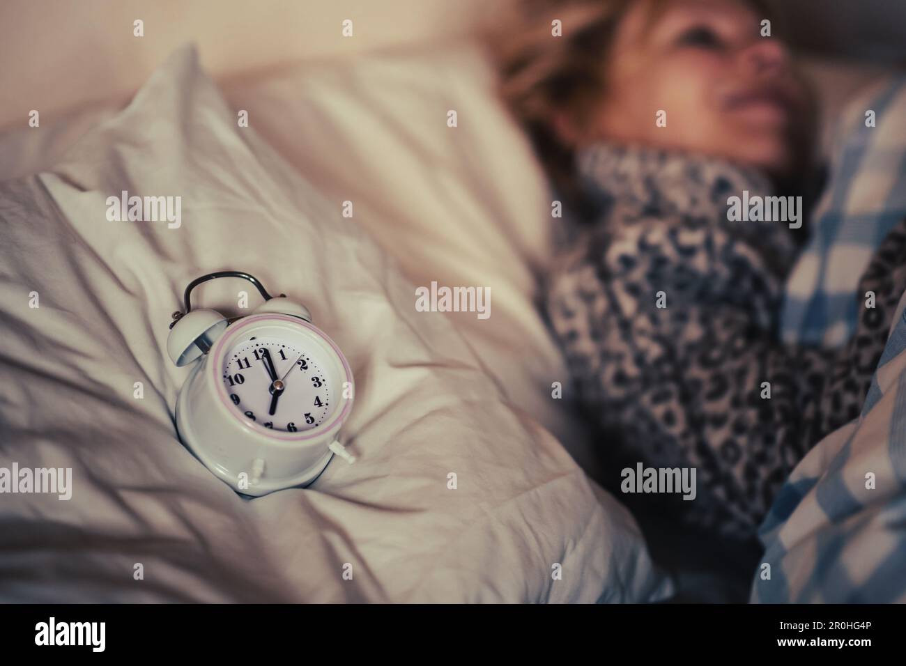 Alarm clock on the pillow and a sleeping woman. The concept of sleep ...