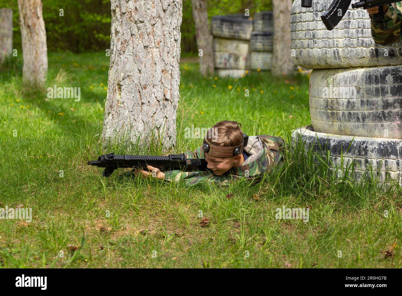 Boy weared in camouflage playing laser tag in special forest playground ...